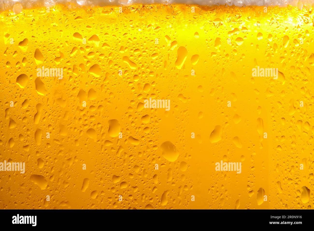 Glass of tasty cold beer with foam and condensation drops as background ...