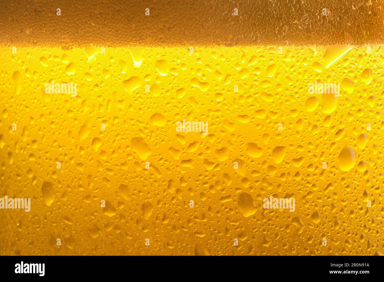 Glass of tasty cold beer with foam and condensation drops as background ...