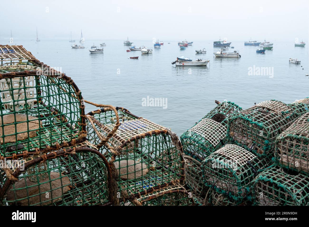 Fishing baskets and fishing boats in the fishing port of Cascais at fog ...
