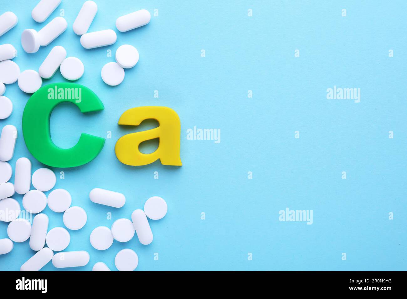 Calcium symbol made of colorful letters and white pills on light blue ...