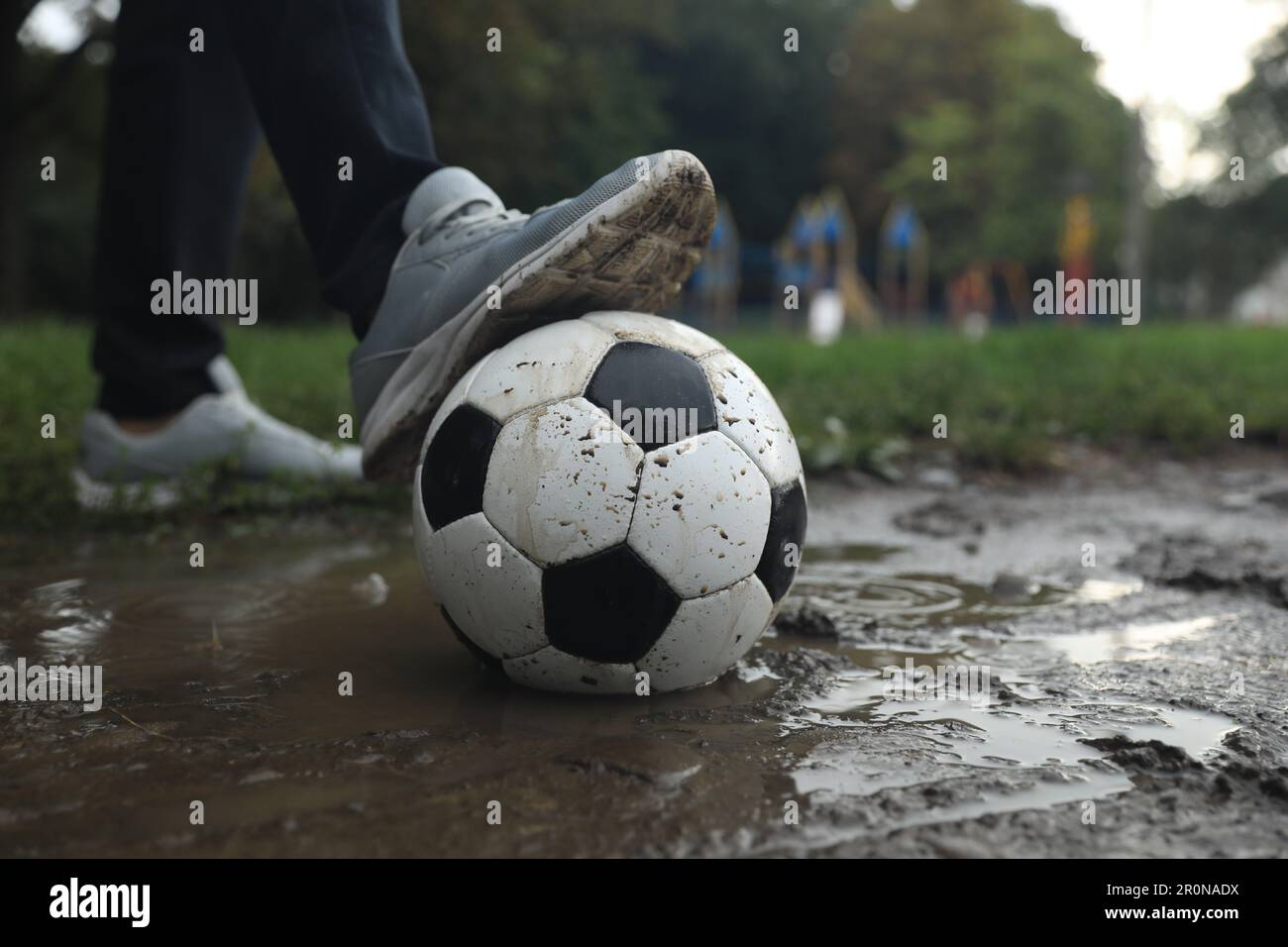 Man with dirty soccer ball in puddle outdoors, closeup Stock Photo - Alamy