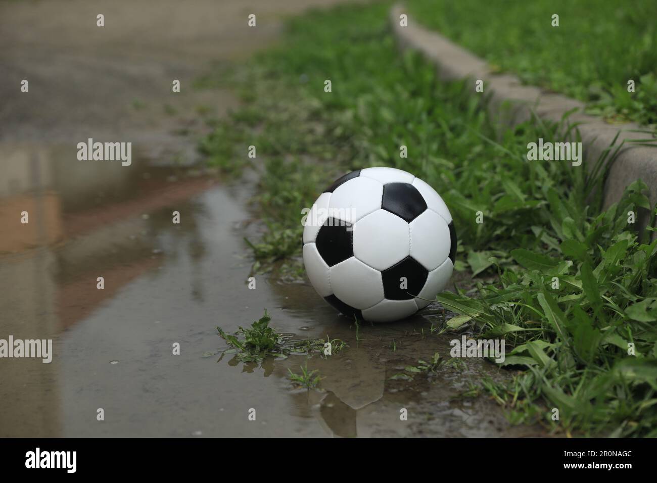 Soccer ball in puddle outdoors, space for text Stock Photo - Alamy