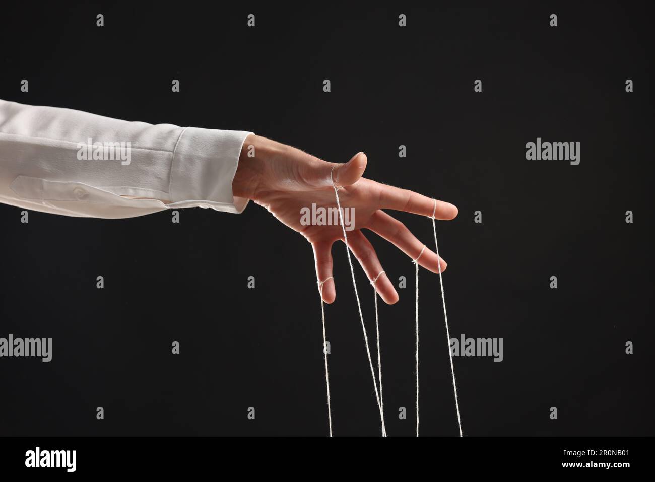 Woman pulling strings of puppet on black background, closeup Stock ...
