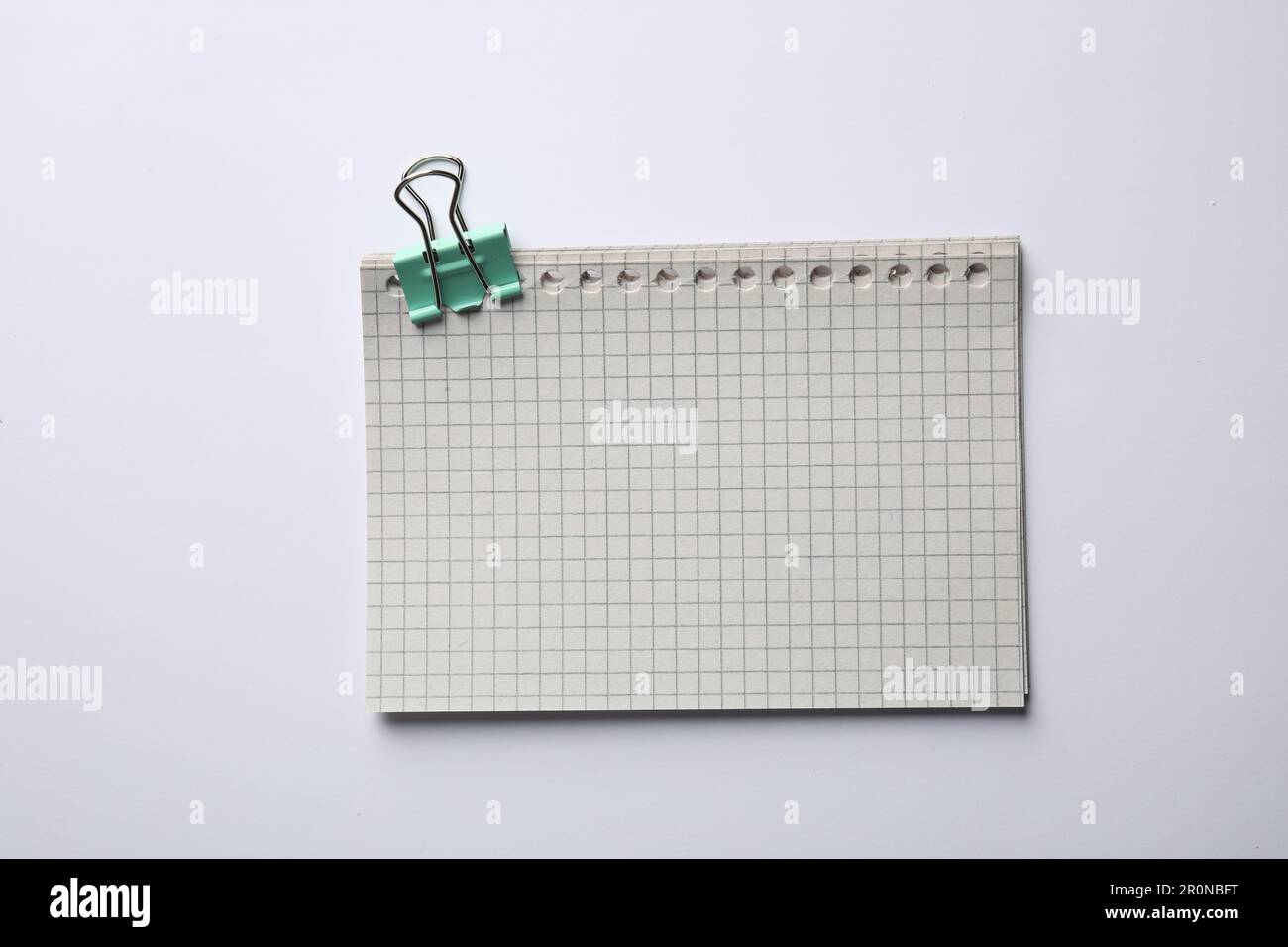 Checkered sheets of paper with binder clip on white background, top ...