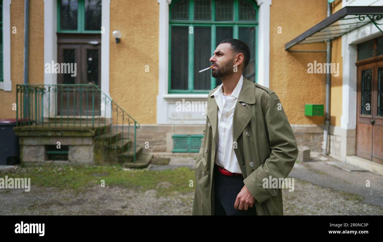One serious Arab man light a cigarette while standing outside with ...