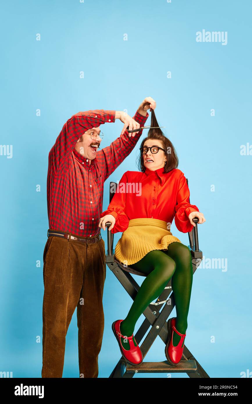 Portrait with scared woman and crazy barber doing new haircut over blue ...