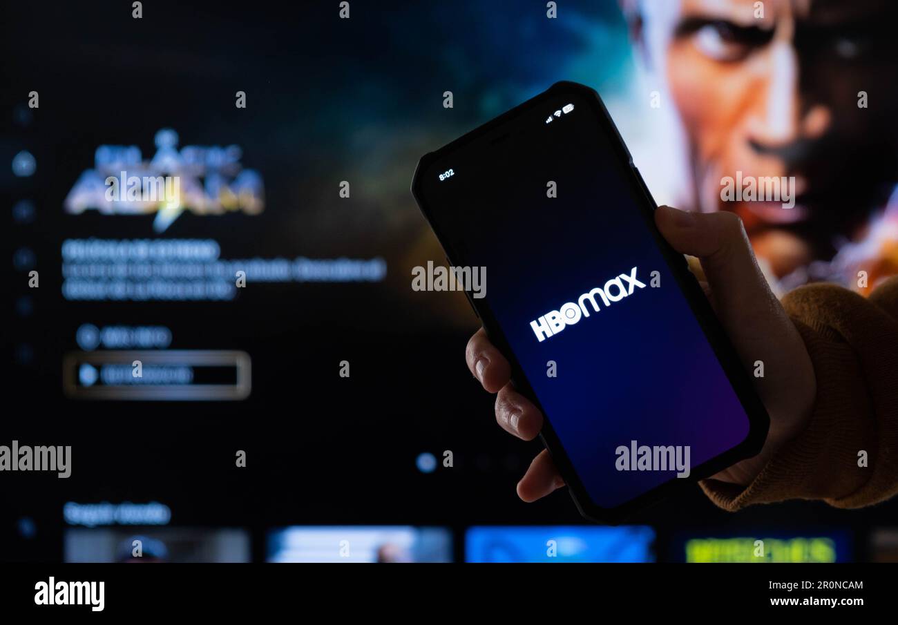 A person holding a mobile phone in front of a computer screen ...