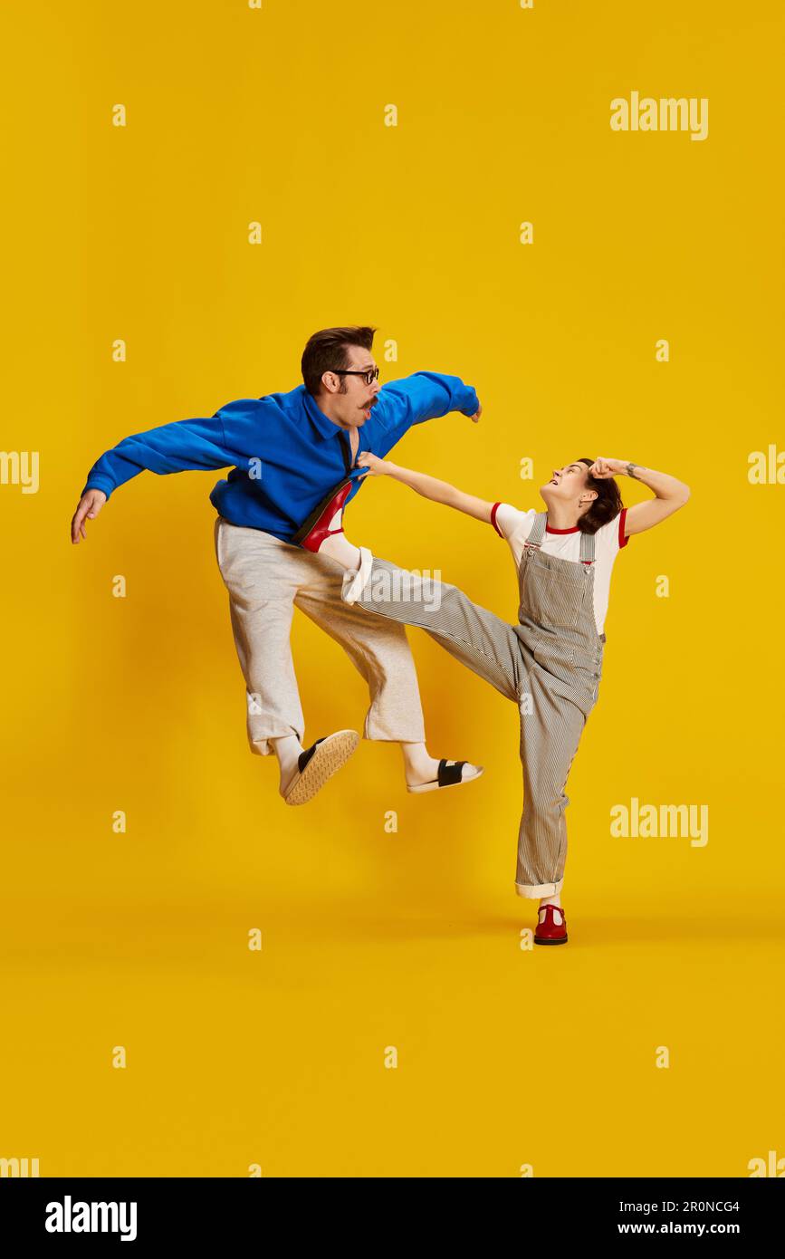 Portrait with funny couple, woman and man playfully arguing over yellow ...