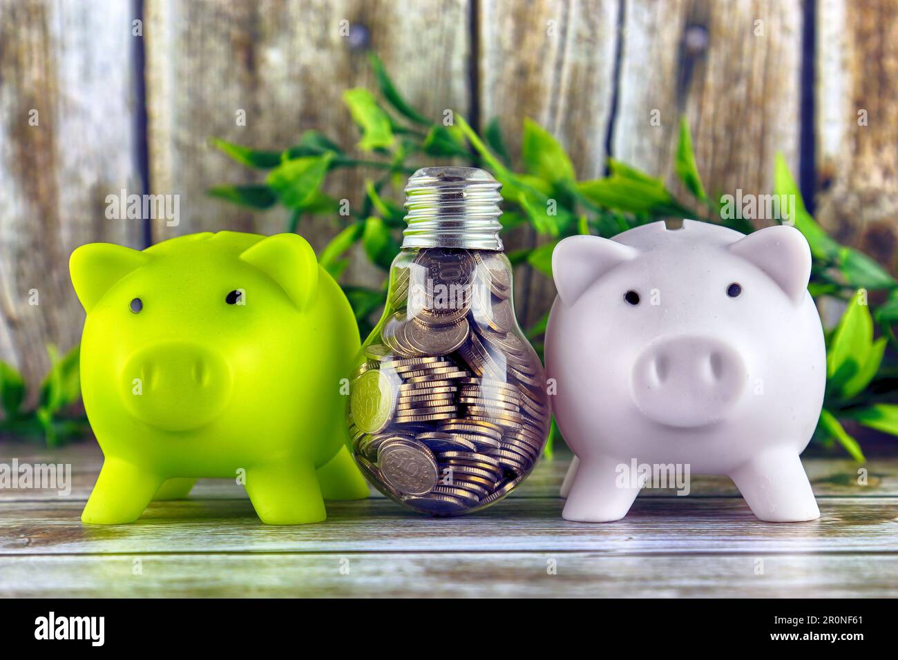 Two piggy banks and coins inside the light bulb. Green eco energy ...
