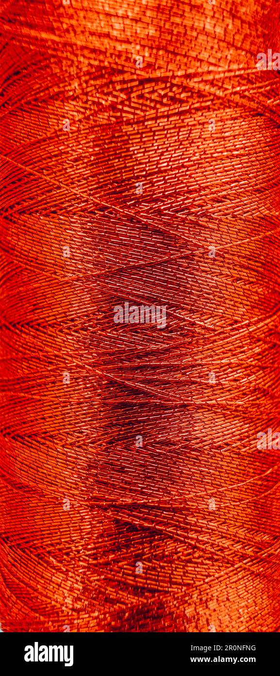 One twisted cylindrical new clean bobbin full of red synthetic threads ...