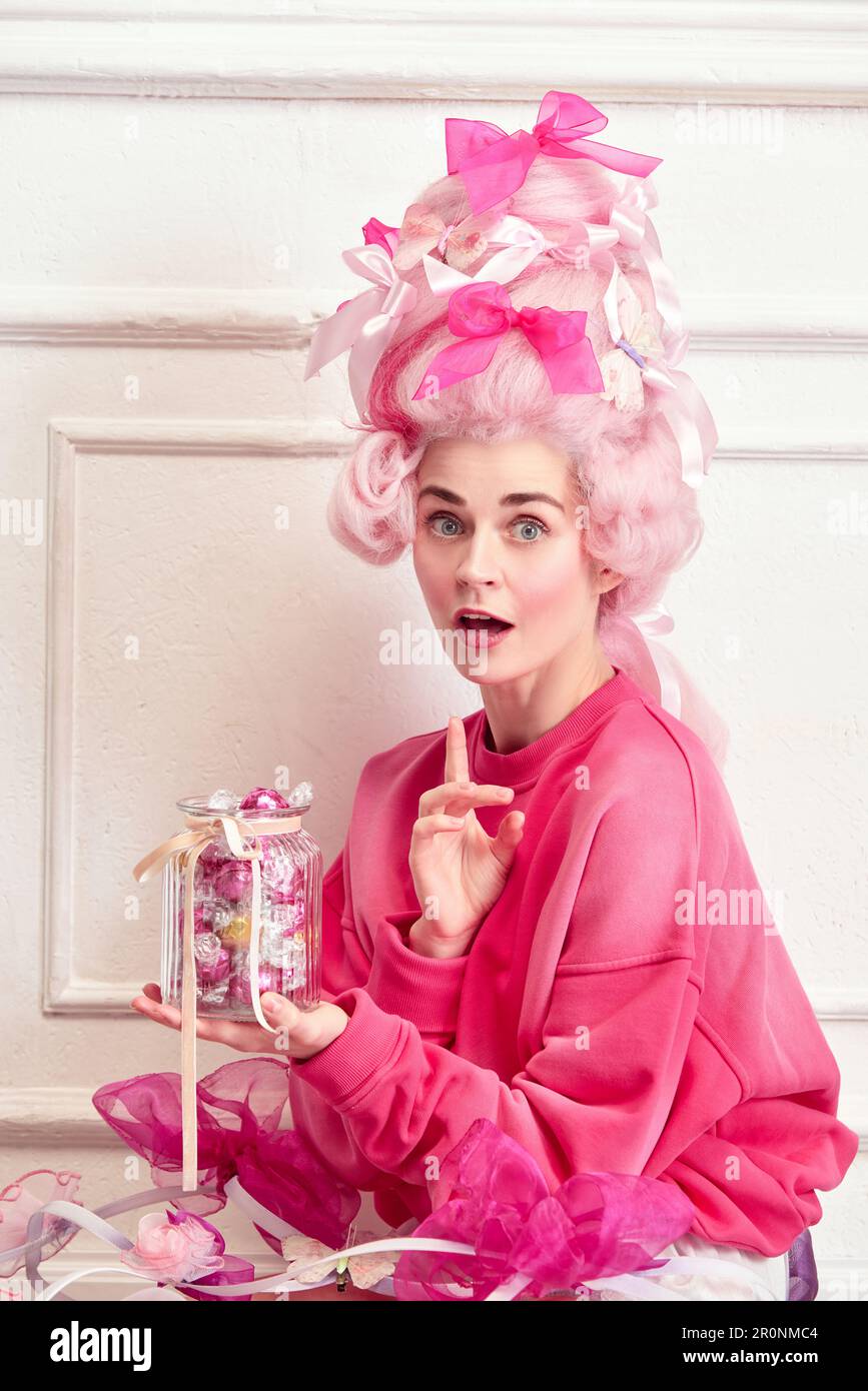 Portrait of charming young girl, princess wearing pink wig and eating ...