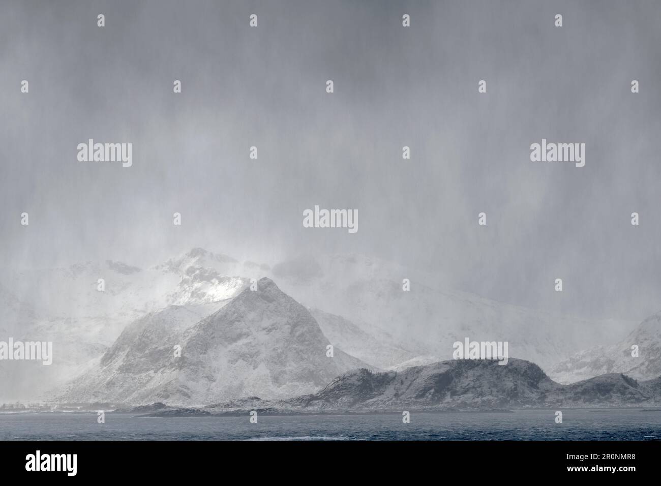 Snow storm over the sea with snowy mountains in the background, Lofoten ...