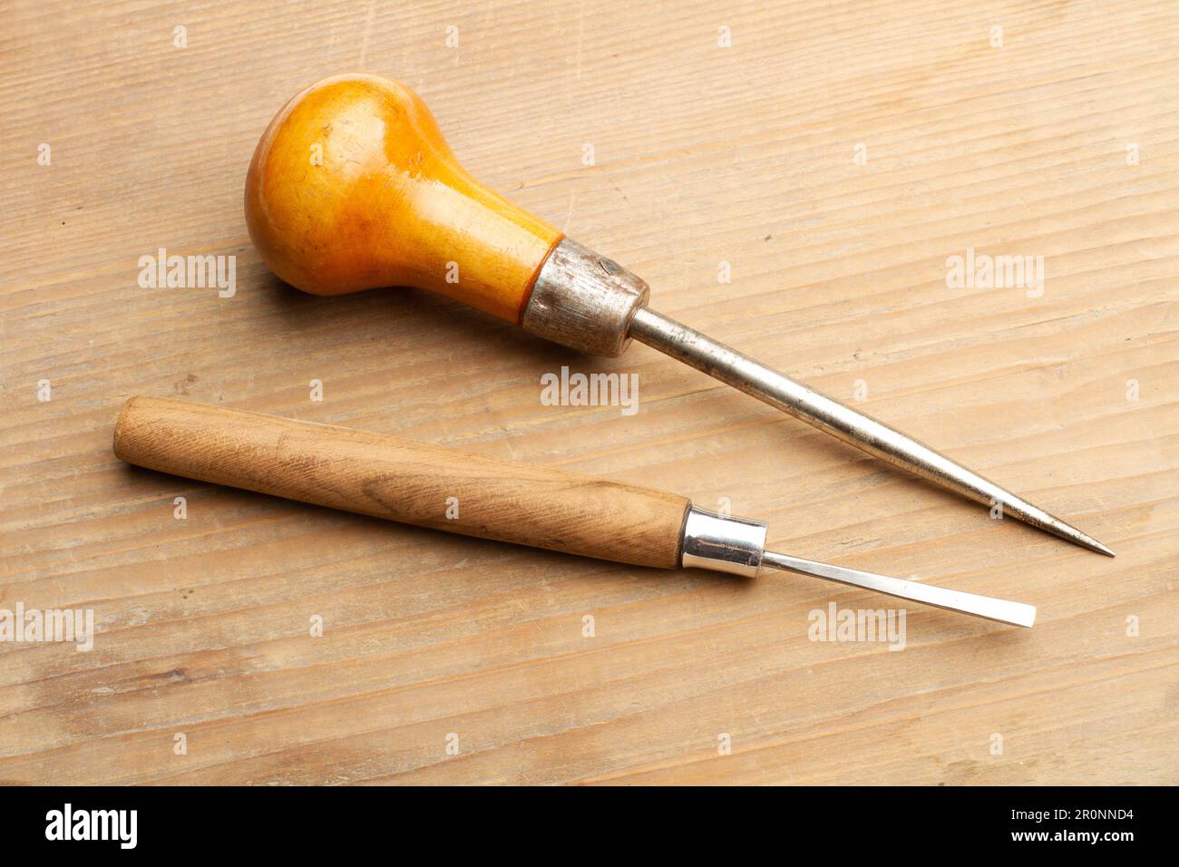 A gouge and an awl with wooden handle on a wooden background with copy ...