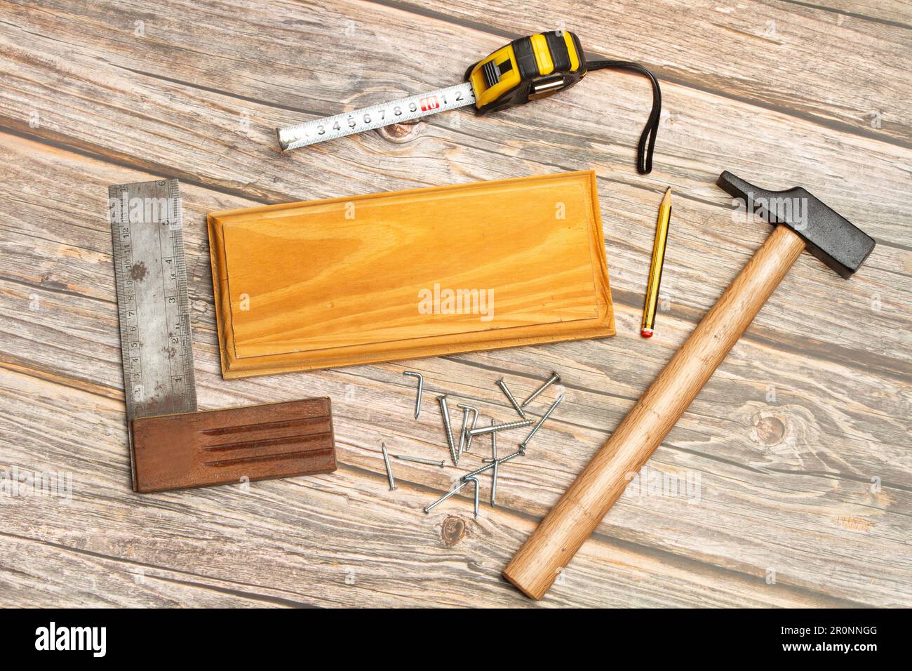 Hammer, try square, pencil, measuring tape and nails on a wooden table ...