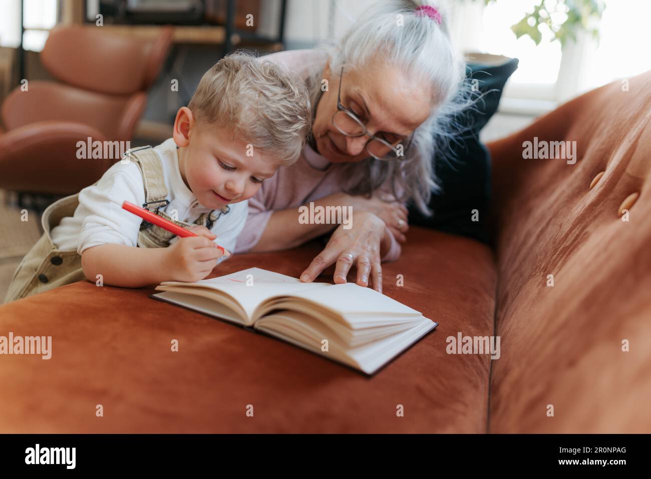 Grandmother drawing in a notepad with her little grandson Stock Photo ...