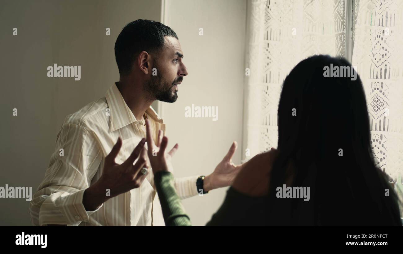 Angry man arguing with girlfriend by window at home. Male person ...