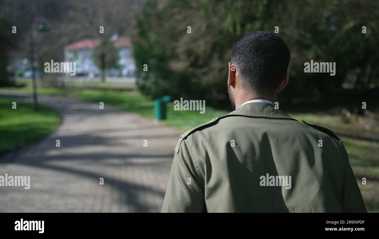 Back of person walking outside at park enjoying sunlight and fresh air ...