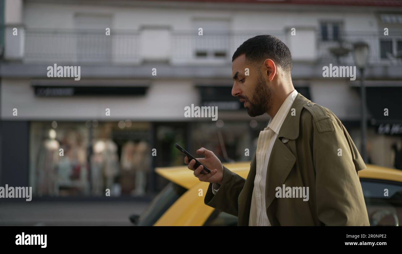 Arab man strolls city street, phone in hand, with camera tracking ...
