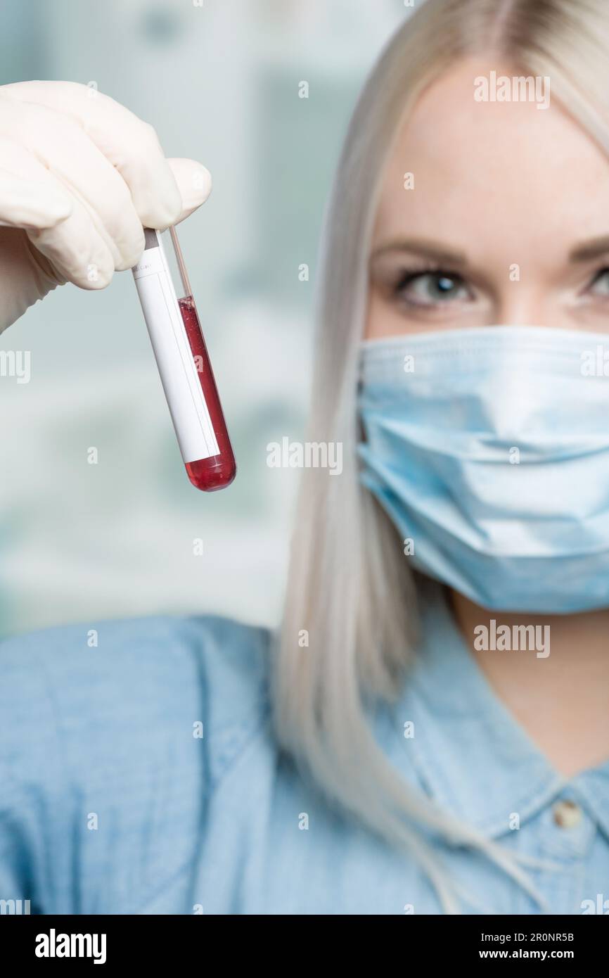 female scientist is handling a blood test tube in front of a laboratory ...