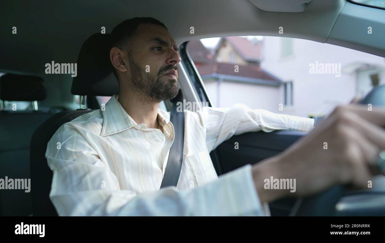 A focused Middle Eastern driver behind the wheel with a pensive ...