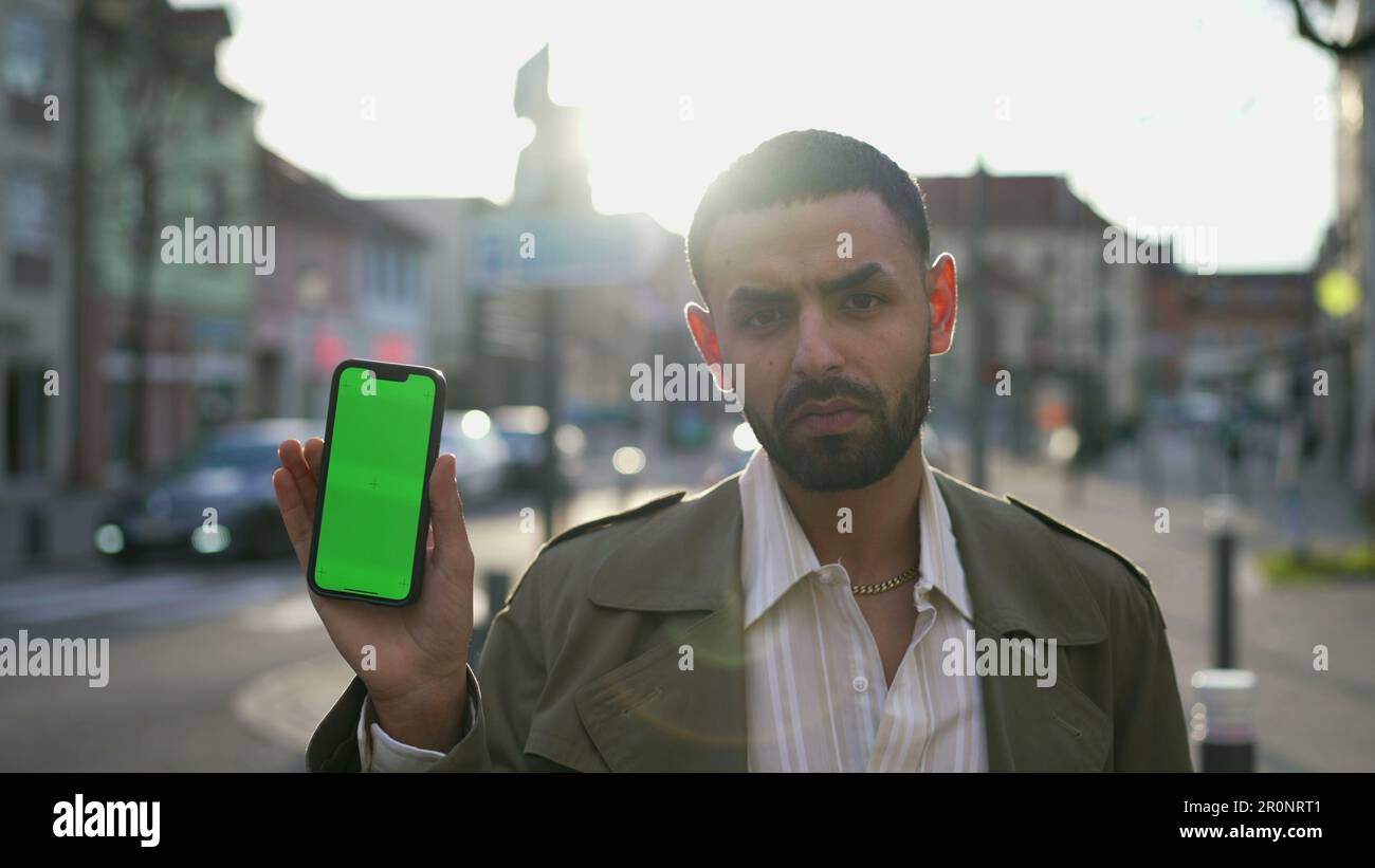 A serious young Arab Moroccan man holding cellphone with chroma ...