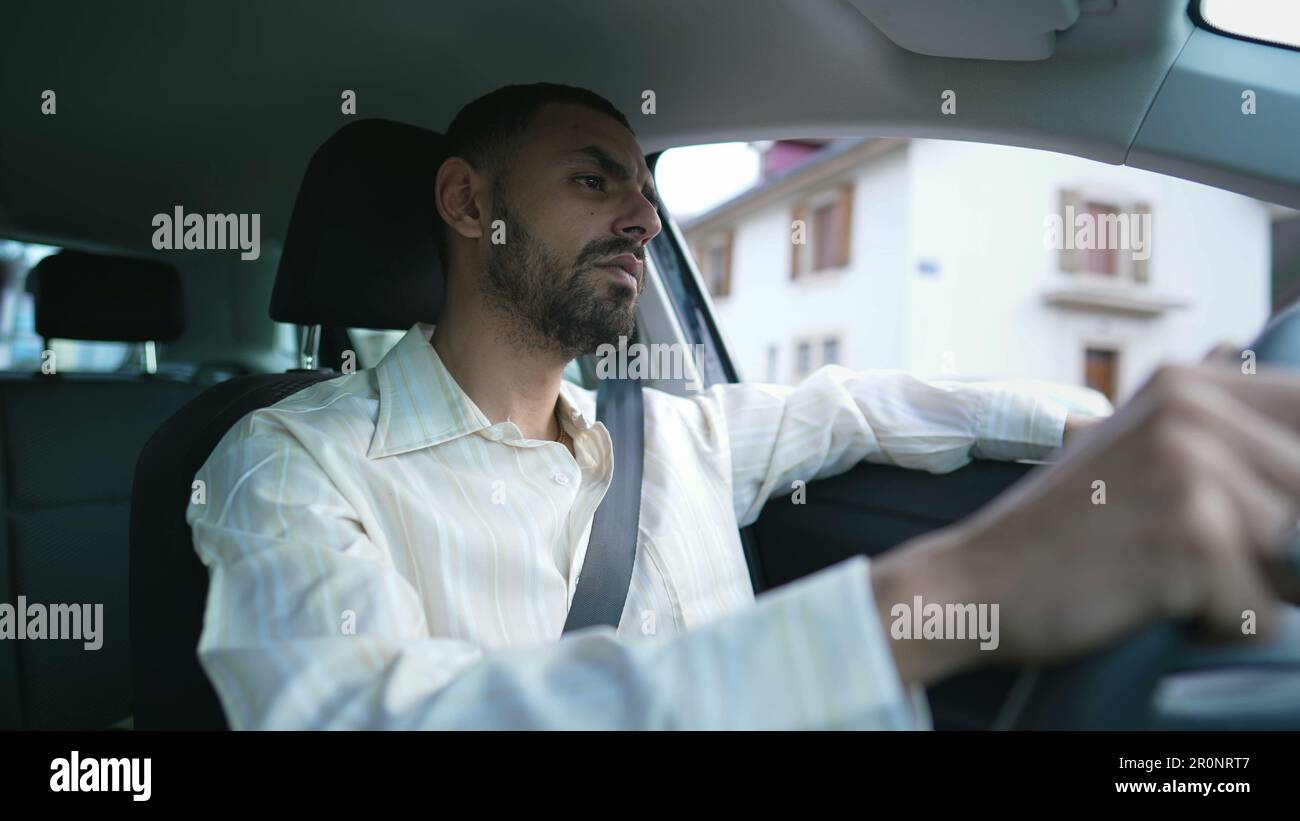 A focused Middle Eastern driver behind the wheel with a pensive ...