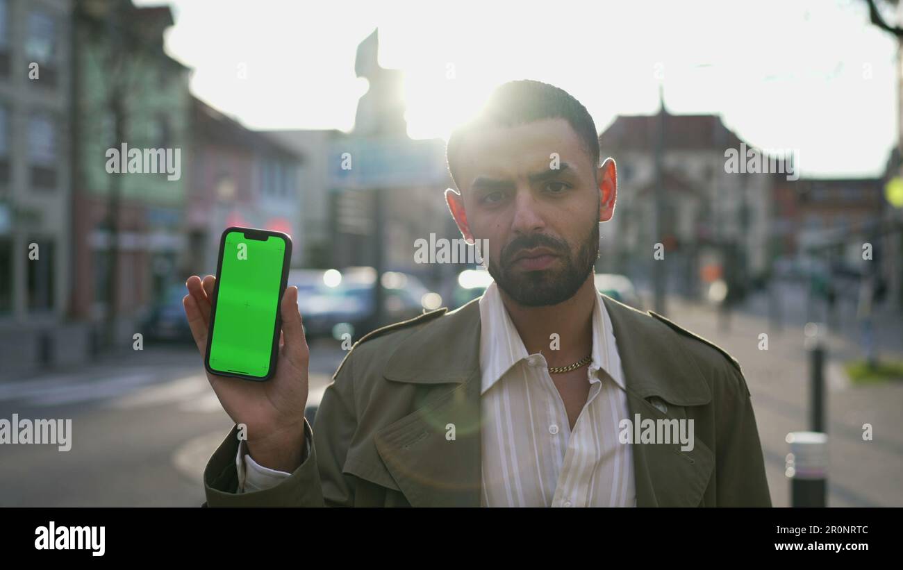 A serious young Arab Moroccan man holding cellphone with chroma ...