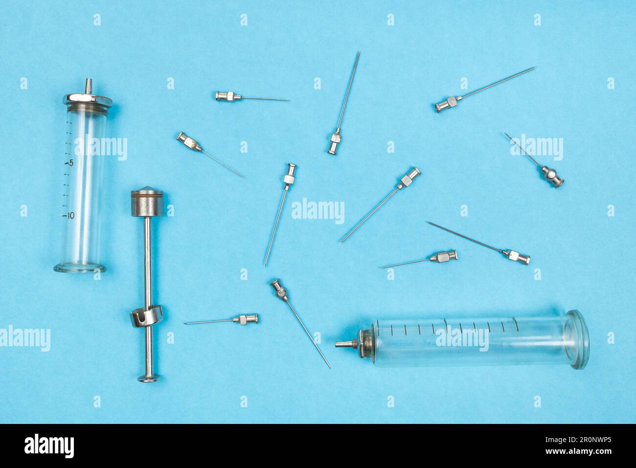 above view of old steel hypodermic needles and glass syringes on blue ...