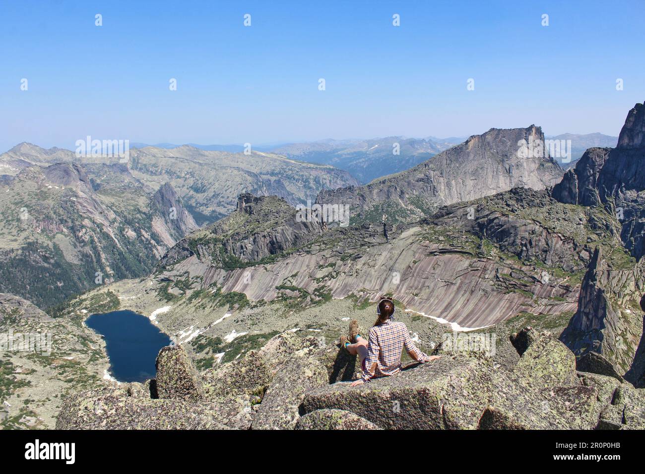 Woman tourist sits on a rock high in the mountains. Panoramic view of a ...