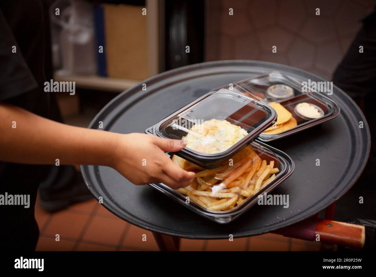 A view of an employee preparing to pack several food to-go containers ...