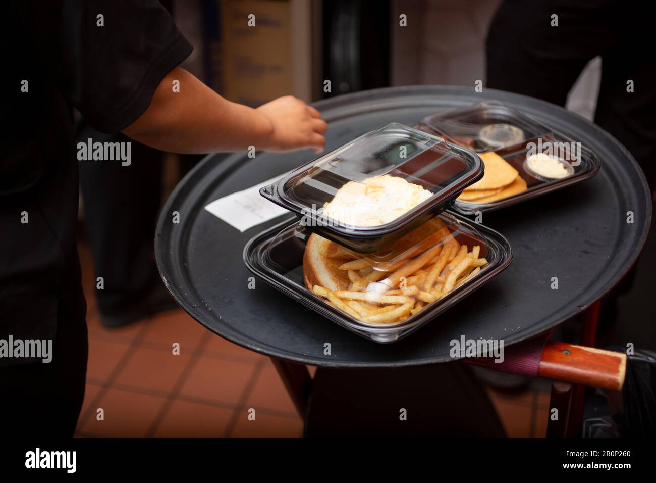 A view of an employee preparing to pack several food to-go containers ...