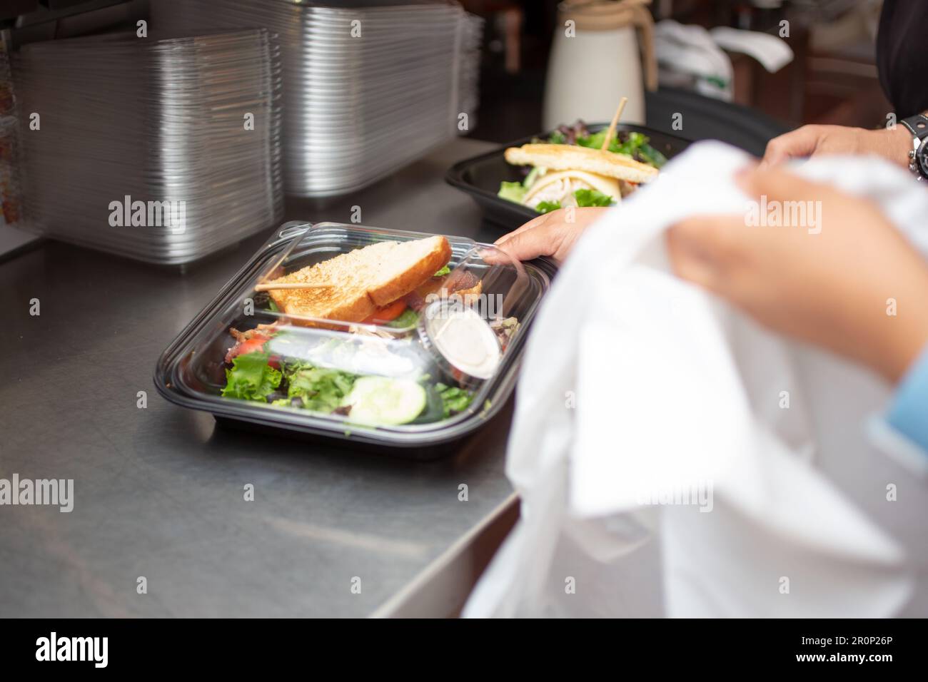 A view of an employee preparing to pack a food to-go container, in a ...