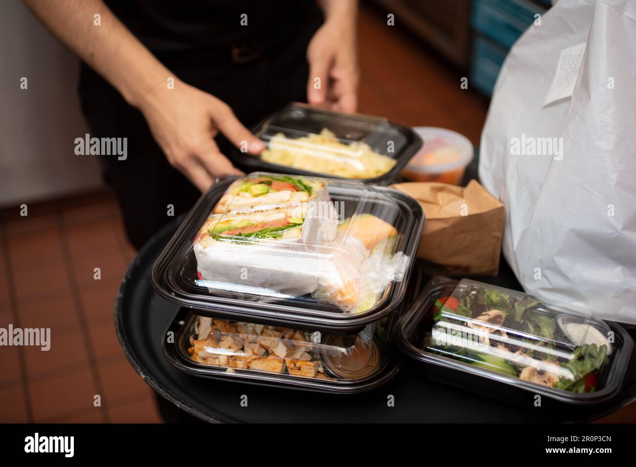 A view of an employee preparing to pack several food to-go containers ...