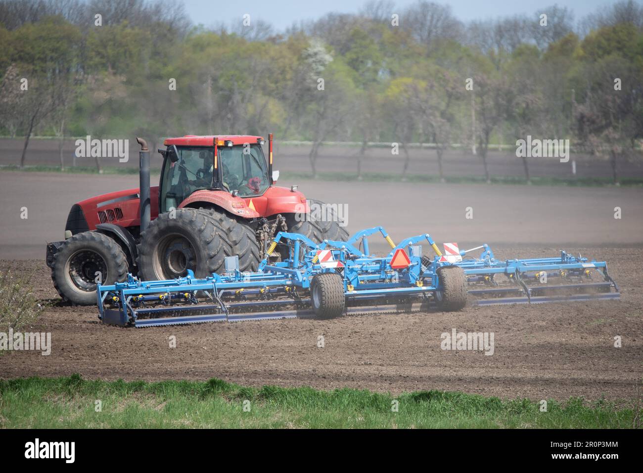 With the help of a sturdy tractor, a cultivator breaks up the soil ...