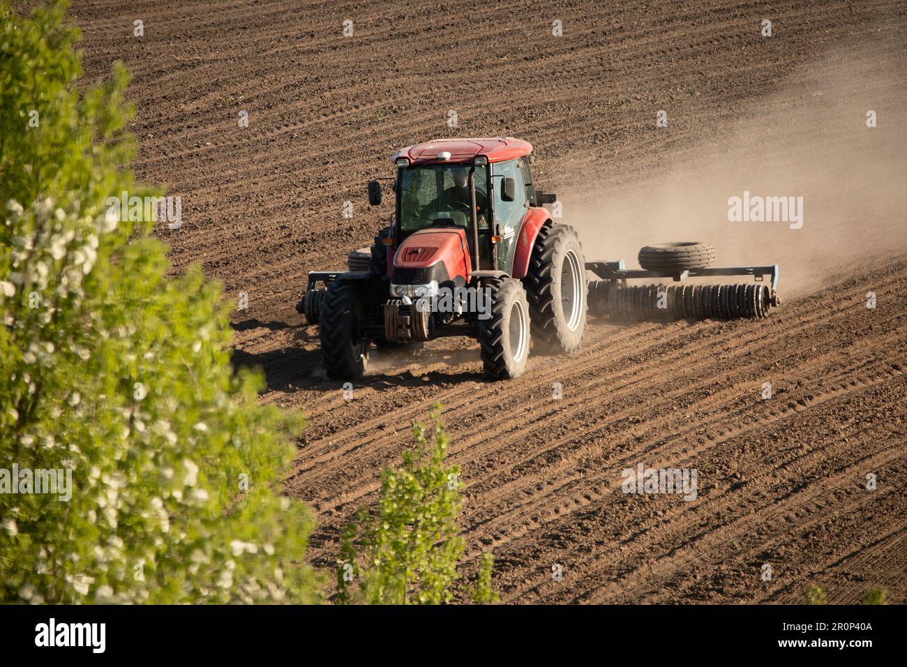 tractor with a cultivator attachment in the process of tilling a large ...