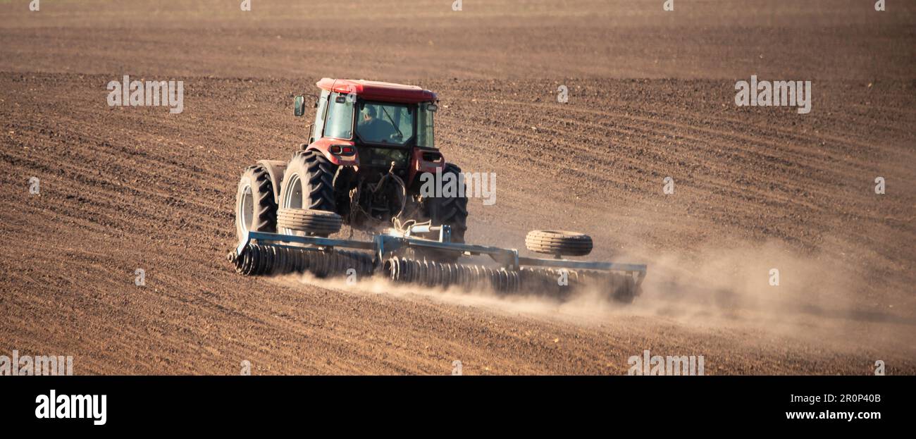 powerful tractor with a cultivator attachment, plowing through the soil ...