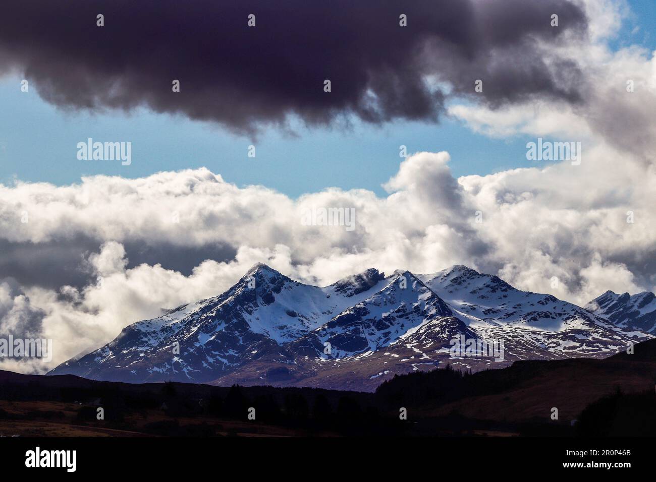 A scenic landscape featuring snowy mountains under a dramatic sky in ...