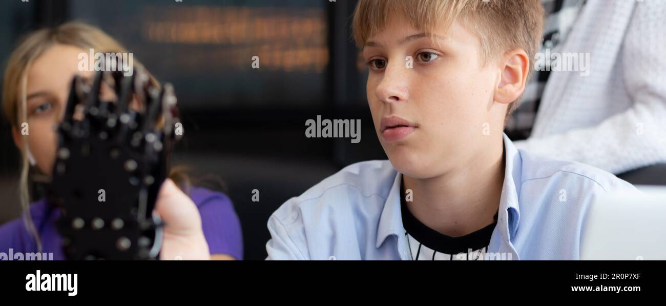 Caucasian two teenager students learning robotic arm in classroom ...