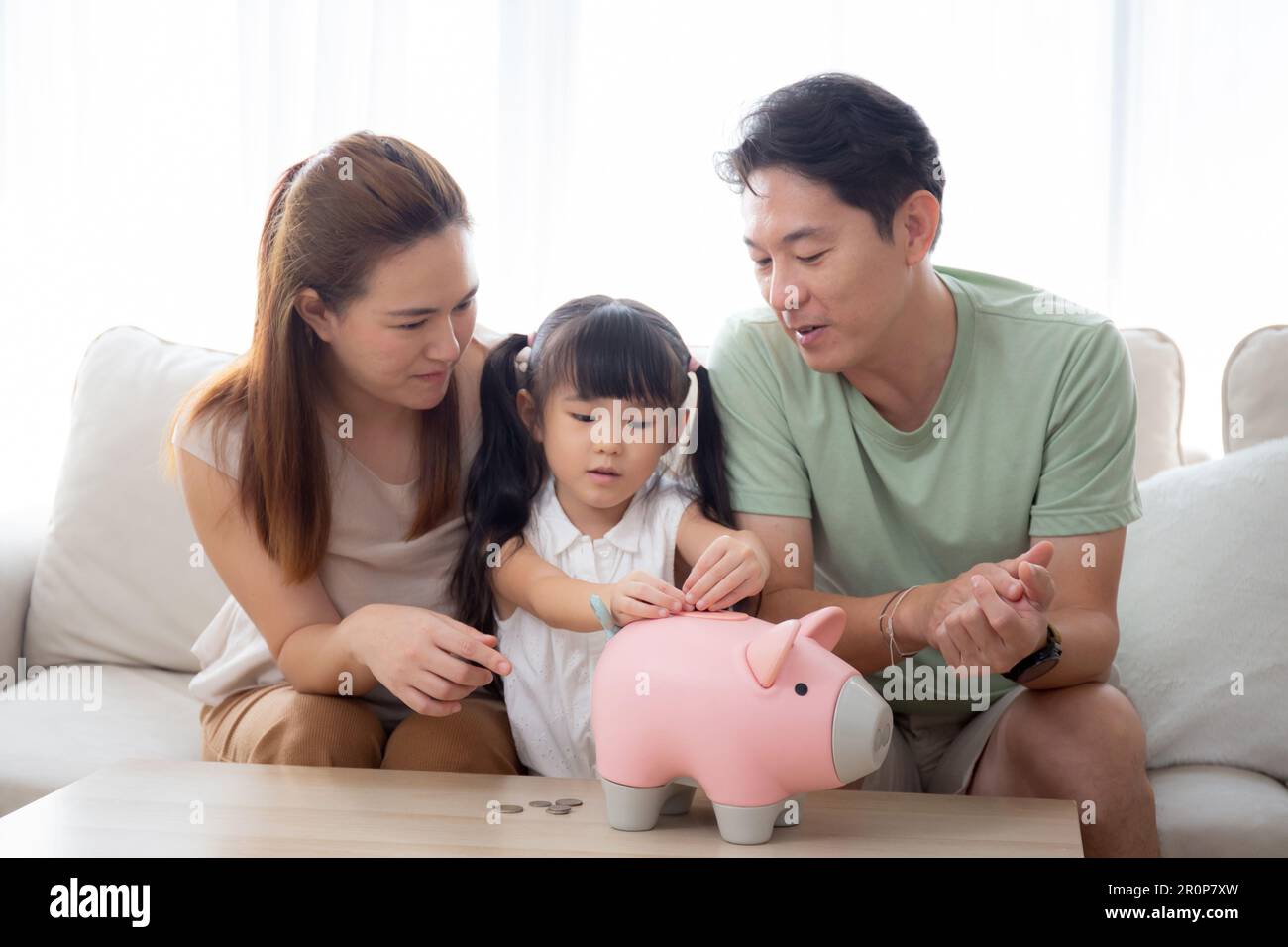 Happy asian family father and mother and daughter sitting on sofa planning finance with saving ...