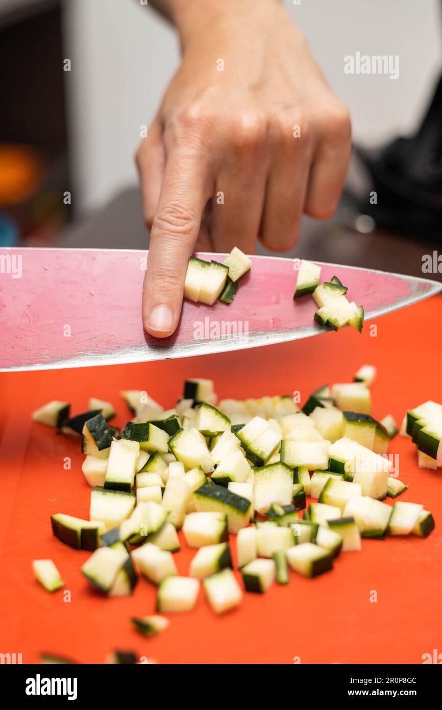 cut into squares a zucchini with kitchen knife, healthy food ...
