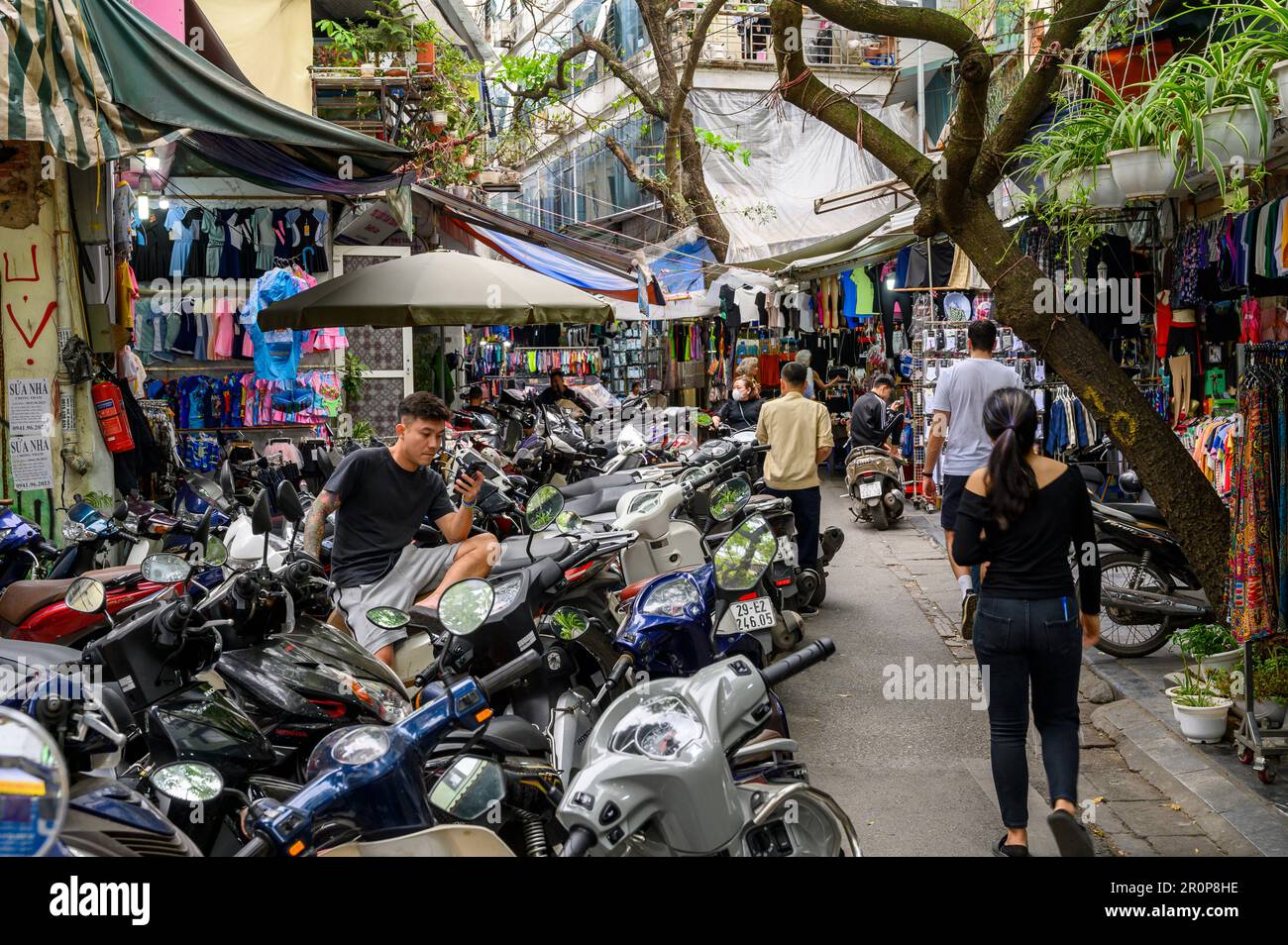 Narrow street in the old quarter packed with parked mopeds and small ...