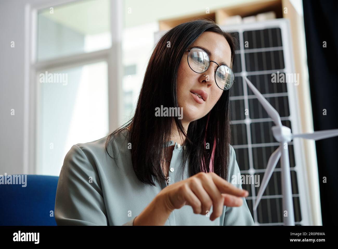 Pensive woman spinning blades of wind turbine thinking about ...