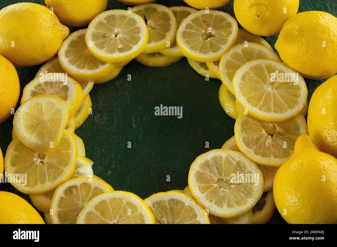 whole and sliced lemons arranged in a circular pattern on a green ...