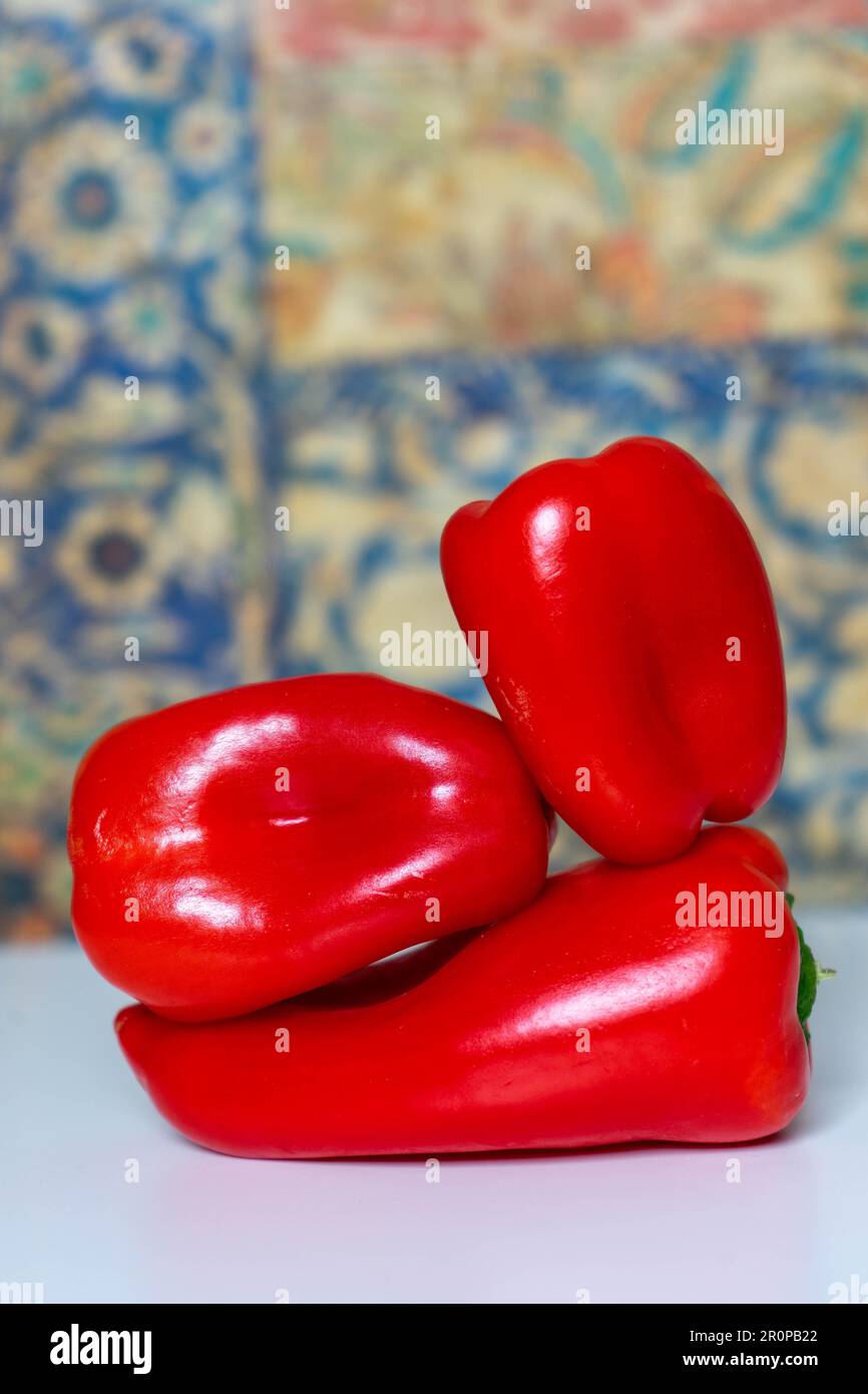 Three small peppers, one red, one yellow and one orange, arranged on ...