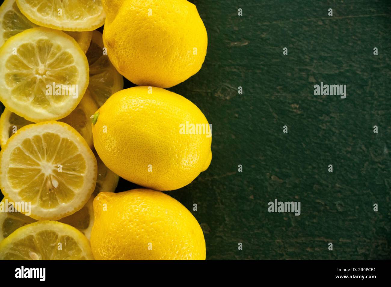 row of whole and sliced lemons creating a border on a green rustic ...