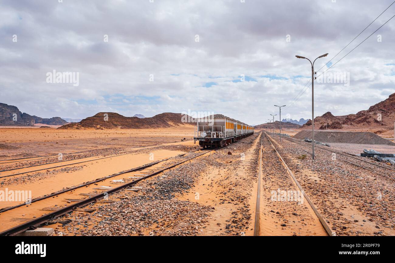 Old unused train at Wadi Rum train station, overcast sky above sandy ...