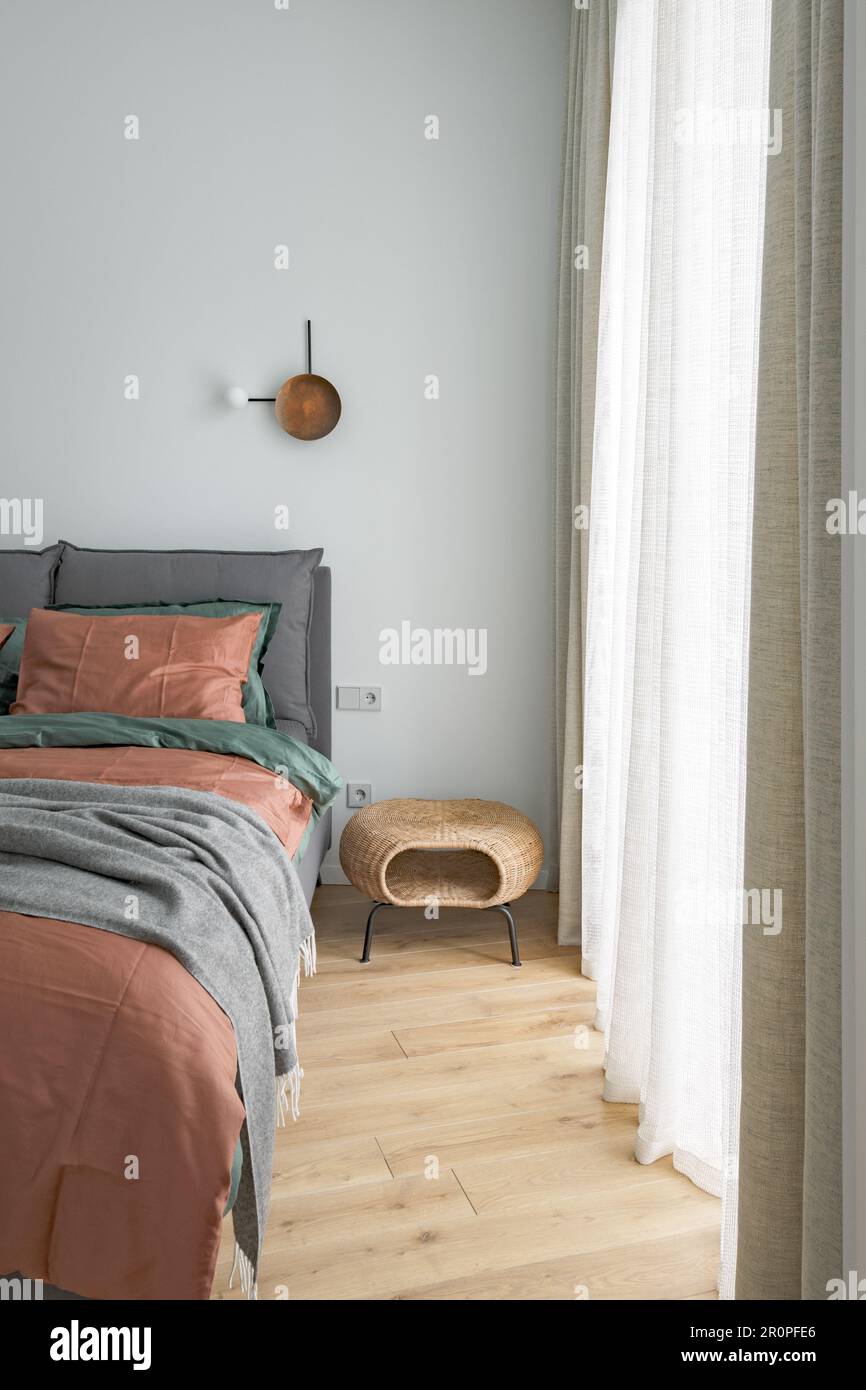 Bedroom interior with rust color linen and cushions on a bed, grey ...