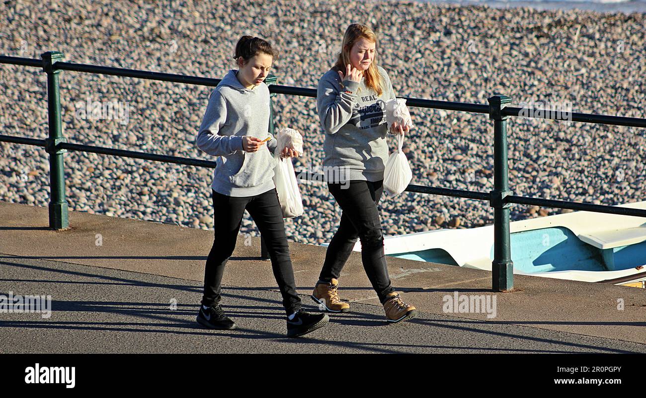 SIDMOUTH, DEVON, UK - JANUARY 19, 2017 two women walking on the sea ...