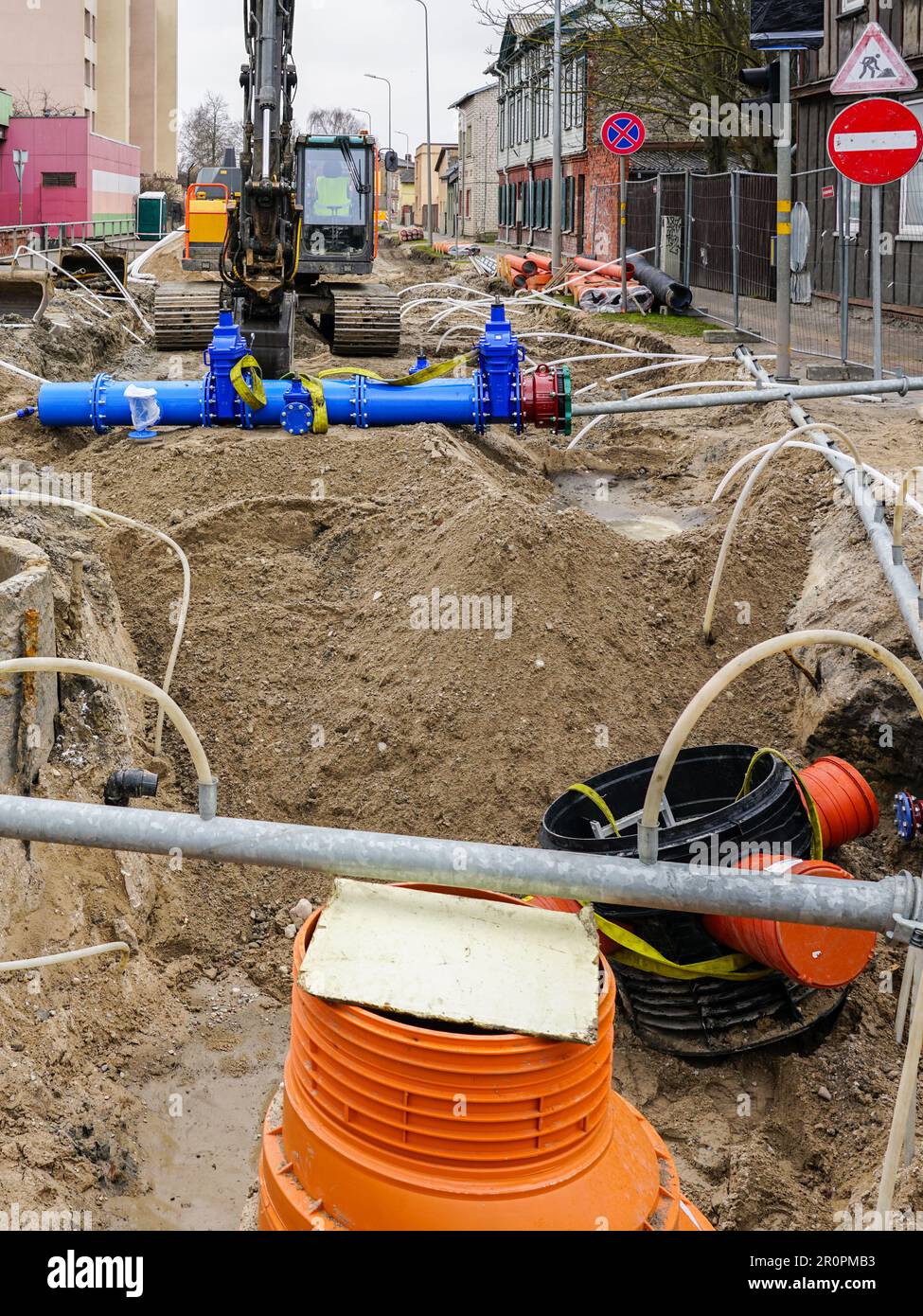 Underground pipe replacement trench on city street, large plastic wells ...