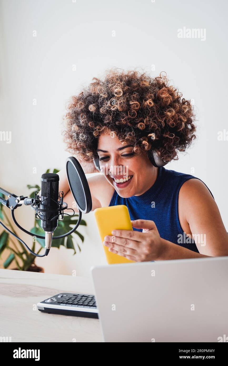 African host woman recording podcast using mobile phone at home studio ...